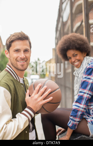Smiling man with basketball standing at sports court Stock Photo - Alamy
