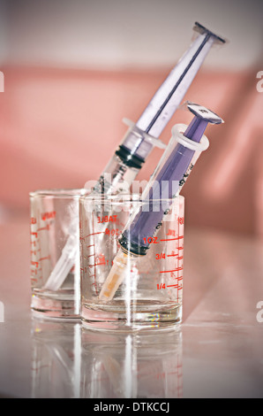 Syringe and a glass measuring cup Stock Photo - Alamy