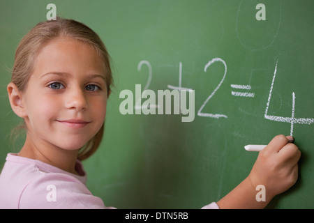 Smiling schoolgirl writing a number Stock Photo - Alamy