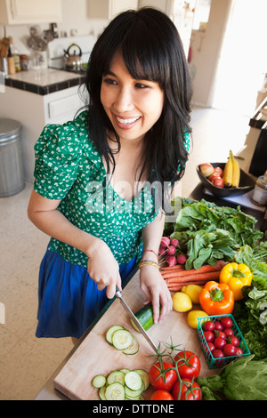 Smiling black woman cutting vegetables in modern kitchen interior Stock ...