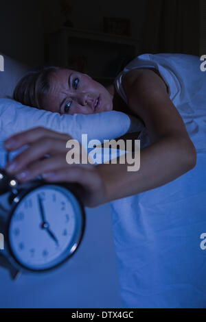 Blonde woman stopping her alarm clock Stock Photo - Alamy