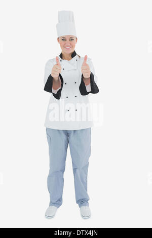 Smiling female professional gesturing thumbs up while sitting at desk ...