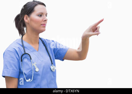 Female nurse pointing at invisible screen against white background ...