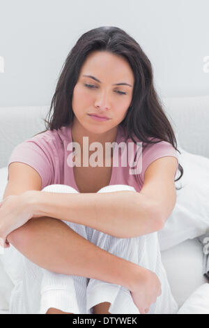 Woman sat on bed thinking Stock Photo - Alamy