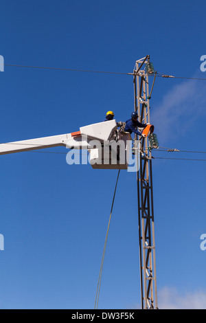 Engineers working on high-tension power-lines are silhouetted against ...