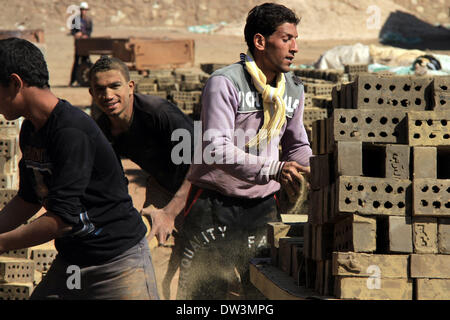 Helwan, Cairo, Egypt. 19th Feb, 2014. An Egyptian laborer loads bricks ...