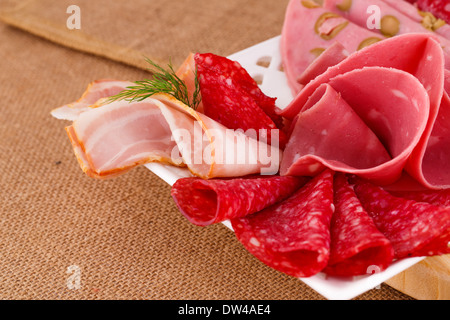 Salami, mortadella and bacon on plate on wooden board Stock Photo - Alamy