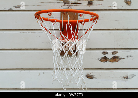 An old basketball ring with a white wooden plate where paint is peeling ...