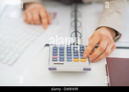 The businesswoman is using a white calculator to check company ...