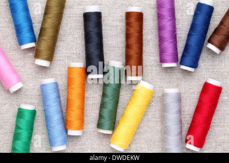 spool of sewing threads on burlap background Stock Photo - Alamy