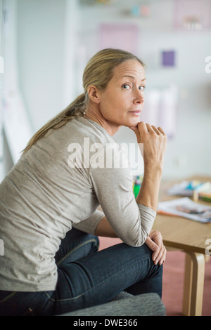 Mature businesswoman with hand on chin in front of white wall Stock ...