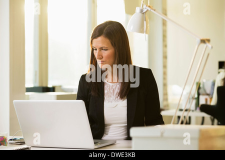 Businesswoman Using Laptop At Desk In Busy Office Stock Photo - Alamy