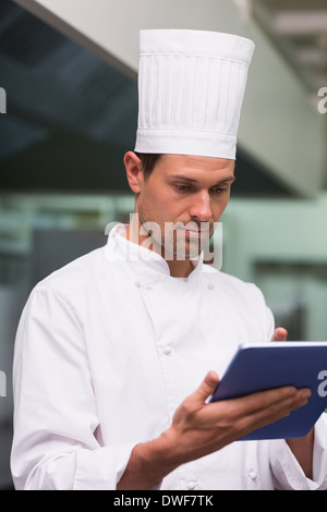 Serious chef using digital tablet beside the vegetables Stock Photo - Alamy