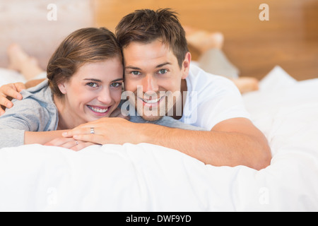 Happy young couple lying on bed at home Stock Photo - Alamy