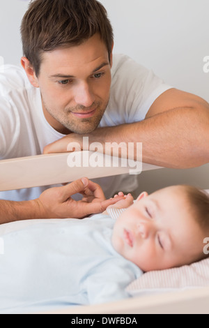 Happy father watching over baby son in crib Stock Photo - Alamy