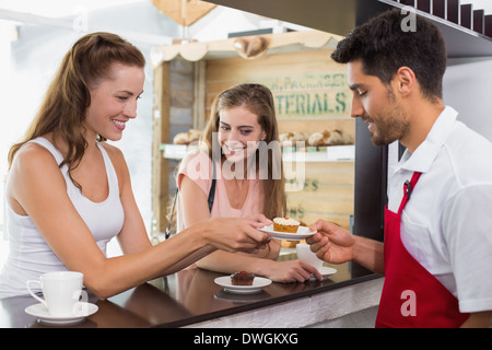 Barista giving pastry to woman at counter in coffee shop Stock Photo ...
