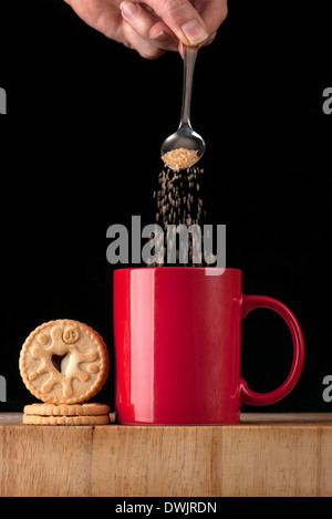 Adding a teaspoon of sugar to a cup of tea on a white background Stock ...