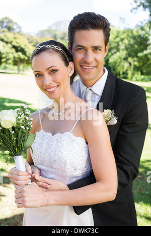 Handsome groom hugging sensual bride from behind on background of an ...