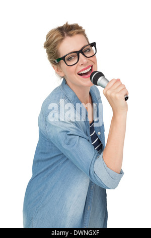 Portrait of smiling mature woman singing in kitchen with wooden spatula ...