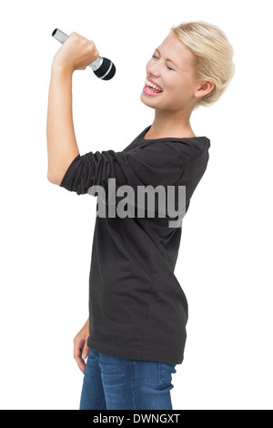 Beautiful young woman with microphone singing karaoke on blue ...