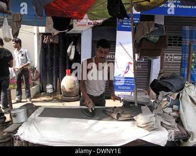 Traditional Indian street laundry man (dhobi) ironing washing on a cart ...