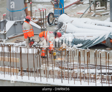 Construction workers and building activity on a snowed winter ...