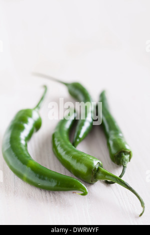 Closeup of four long green chili peppers on light background Stock ...