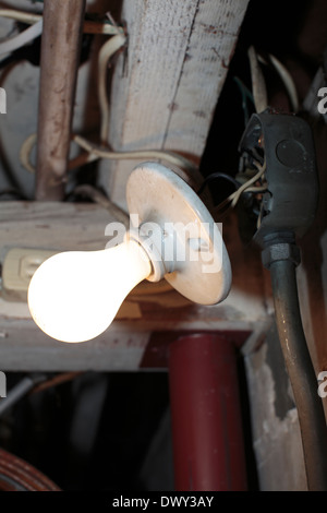 Incandescent light bulb hanging from ceiling over head from roof house ...