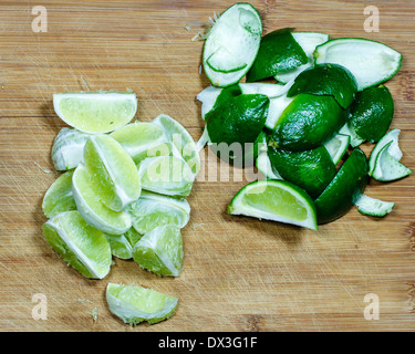 A single piece of cut lime waiting to be peeled next to the peels from ...