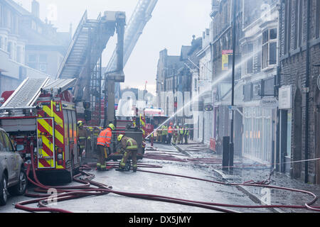 Firefighters work at a damaged building with ladders, debris, and ...