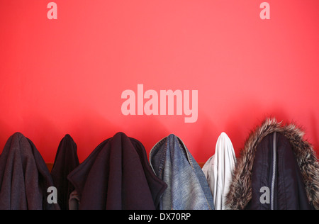 Coats and jackets hanging in a red painted cloakroom Stock Photo - Alamy