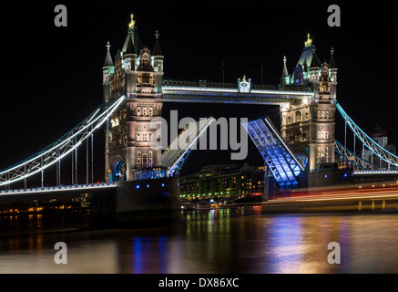 Iconic Tower Bridge lit up at night, lifting to allow brightly lit ...