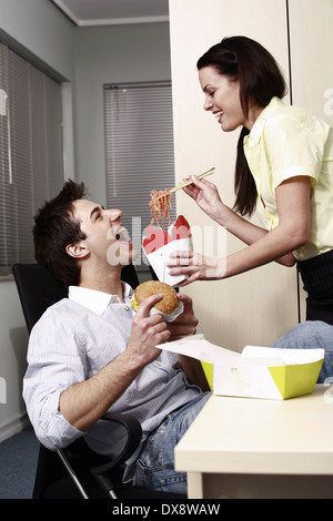 Office worker feeding her colleague Stock Photo - Alamy