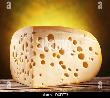 Yellow cheese with holes on a wooden cutting board with grilled green ...