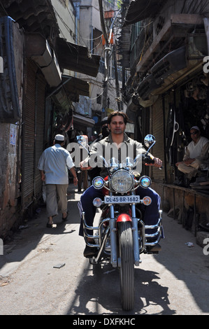 A man on a motorcycle rides on an alley painted and decorated with ...