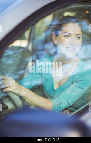 Happy smiling brunette woman driver sitting in new red cabriolet car on ...