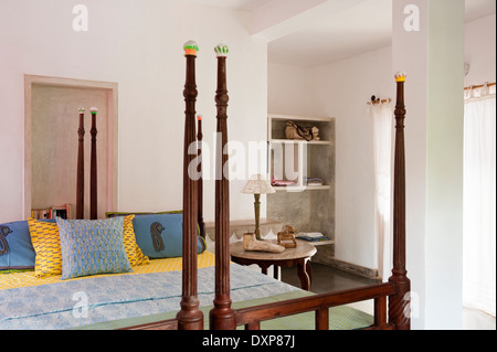 Carved wooden bedposts in modern bedroom with shelving, Indian state of ...