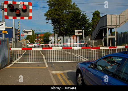 A railway level crossing with the gates down while the train departs ...