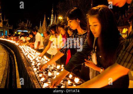 Buddhist devotees pray while they light candles during the full moon ...