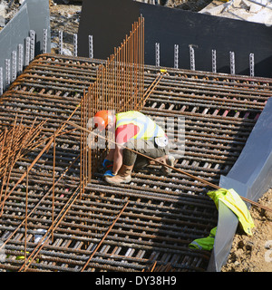 Steel fixer tying reinforcement bars in a bridge foundation base ...