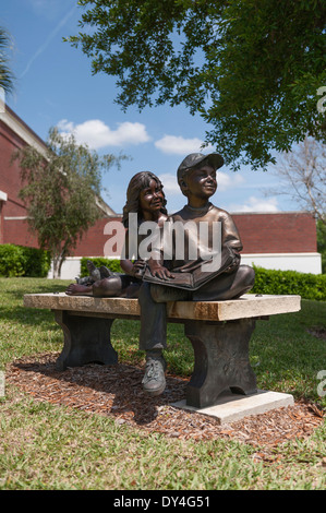 Bronze statue of children reading a book on a bench outside the ...