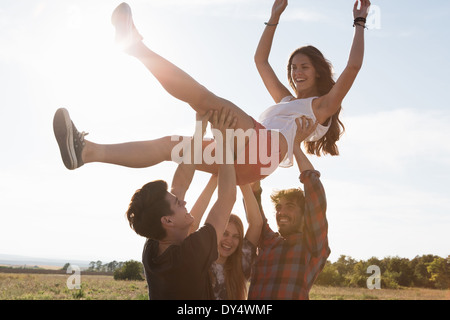Four friends lifting a woman over their heads horizontally up to the ...