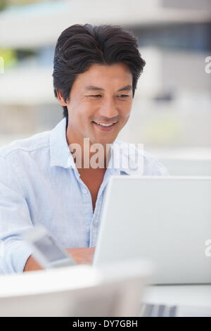 Happy black man using laptop and wireless headphones on blue Stock ...