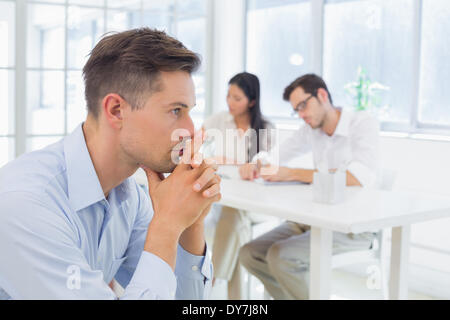 Casual businessman thinking with team behind him in the office Stock ...