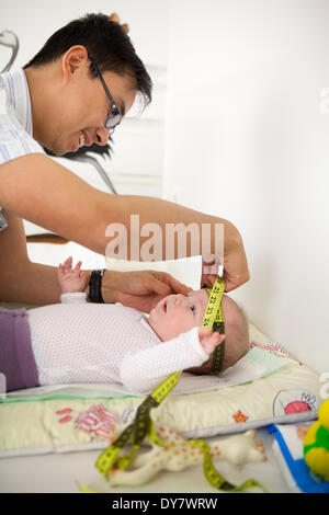 Pediatrician measuring the circumference of a 2 month old baby's head ...