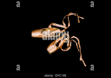 Worn out ballet pointe shoes on the feet of a ballet dancer tying her ...