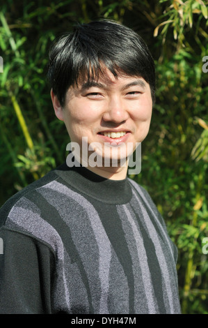 A young chinese man in green medical scrubs with a stethoscope around ...