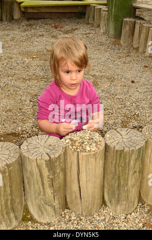 Little girl playing with pebbles at the playground Stock Photo - Alamy