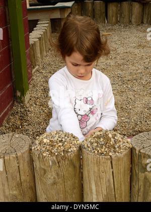 Little girl playing with pebbles at the playground Stock Photo - Alamy