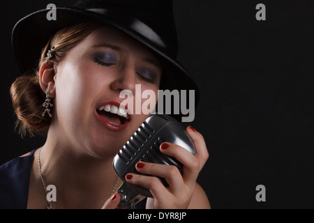 Beautiful jazz singing woman with fedora and retro style microphone ...